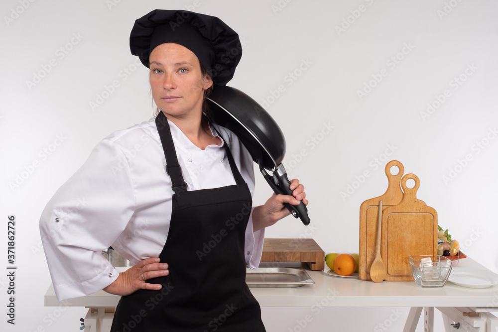 Cook chef woman in restaurant kitchen. Cook is posing with a frying pan ...