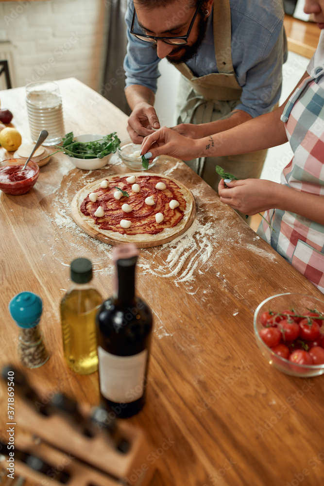 For a tasty pizza. Young couple making pizza together at home. Man in ...