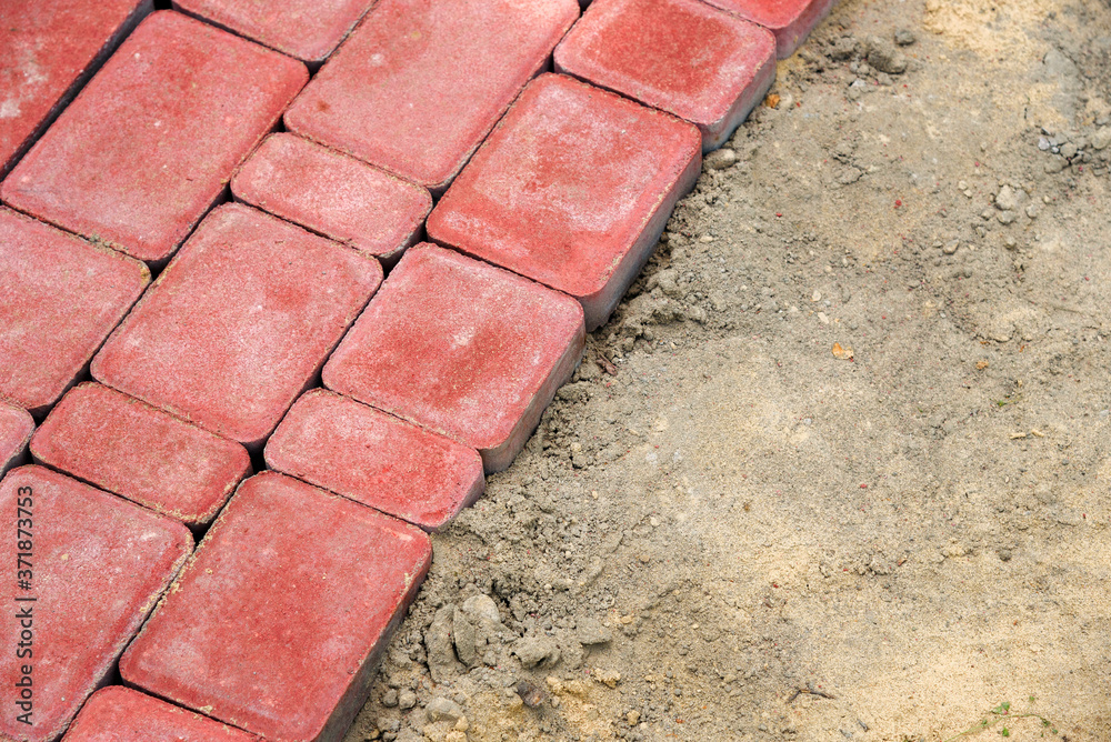 Installation of new road tiles, top view of pavement tiles and sand ...