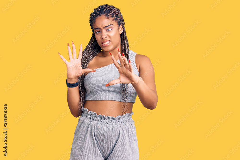 Young african american woman with braids wearing sportswear disgusted ...