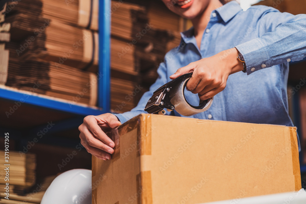 Closeup of Warehouse worker woman packing cardboard box with sticky ...