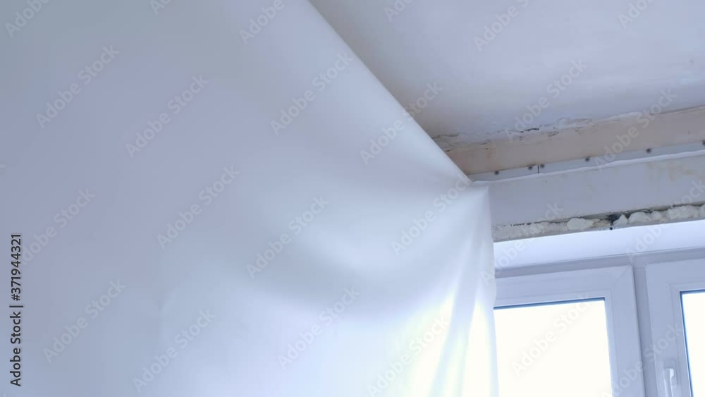 Man builder dismantling of stretch suspended ceiling cuts it using ...