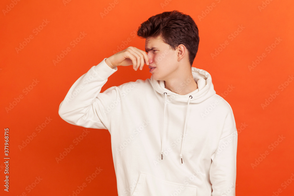 Squeamish teenager in stylish sweatshirt with hood pinching his nose ...