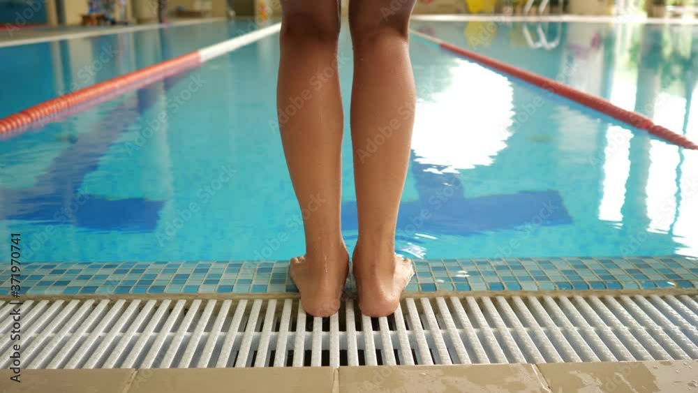 slim young barefoot woman jumps into swimming pool clear water to train ...