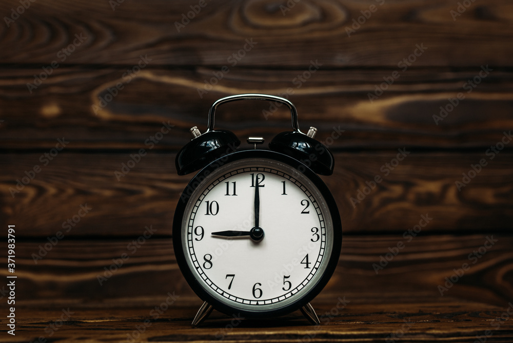 Clock on a wooden background. The clock shows the time of nine o'clock ...