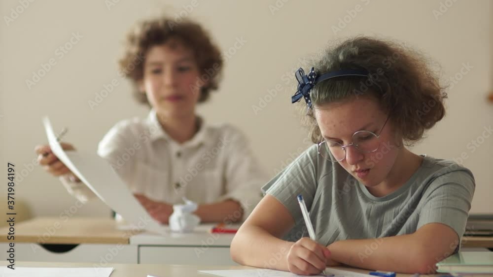 Children at school laugh during the lesson. The boy shows the girl a ...