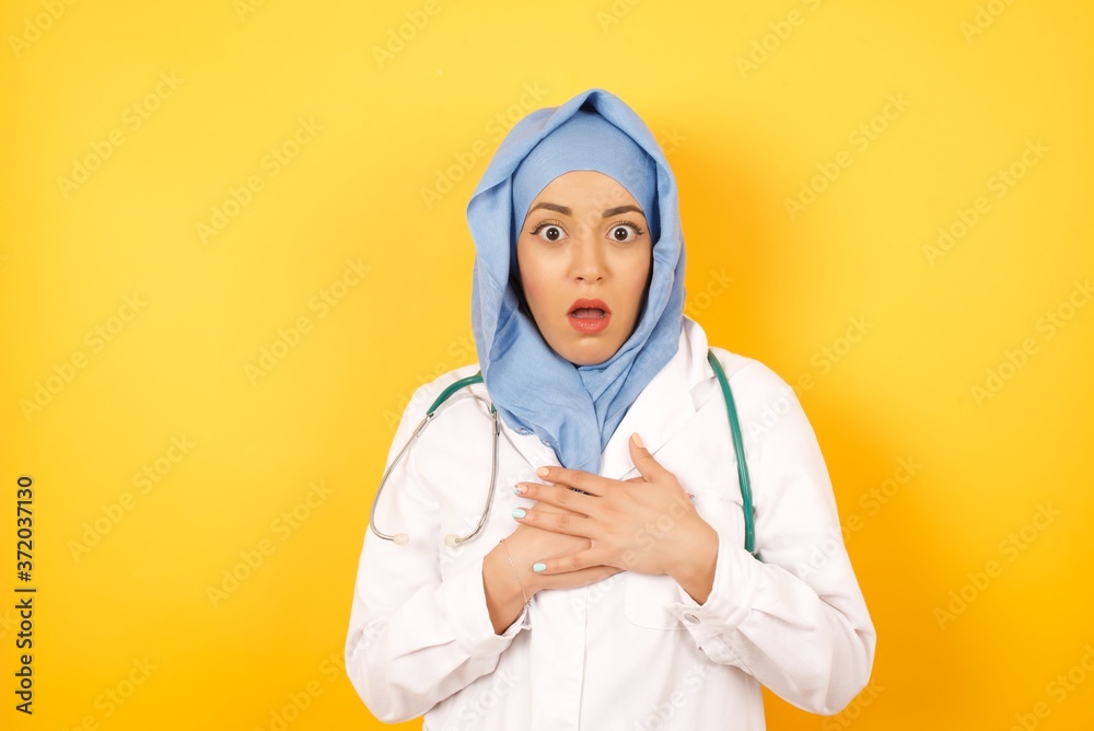 Foto de Scared Young arab doctor woman wearing medical uniform standing ...