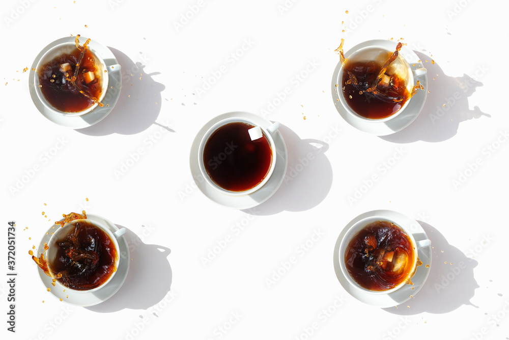 Black coffee in white cups, top view. Sugar lumps are thrown into the ...