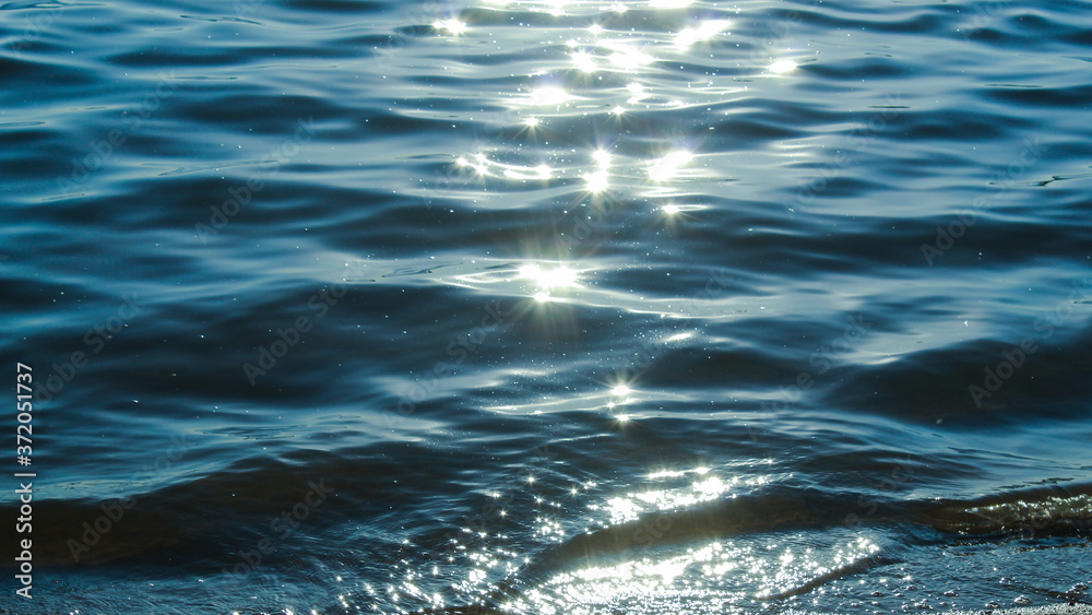 Sun glare in waves of sea water on a tropical beach in summer in nature ...