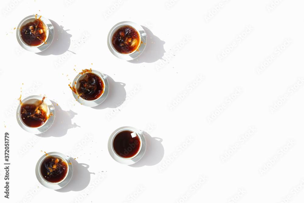 Black coffee in white cups, top view. Sugar lumps are thrown into the ...