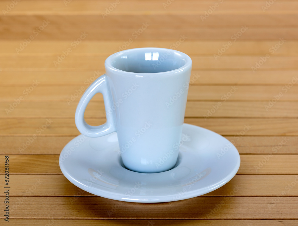An espresso cup and saucer with an upside down handle on a slatted wood ...