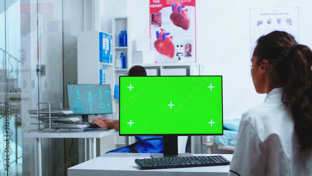 Doctor using computer with green screen mockup in hospital and ...