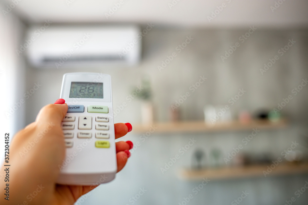 Hand with remote control directed on air conditioner. Home air ...