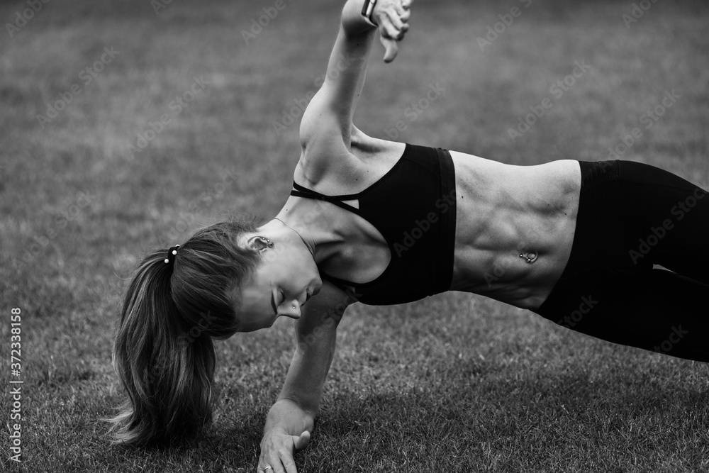 Strong athletic woman working out at the stadium, do a side plank ...