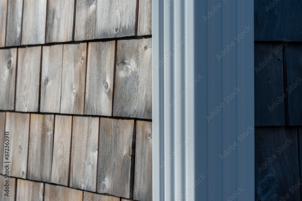 The corner edge of a wall with a wide white molding. The wood has lines ...