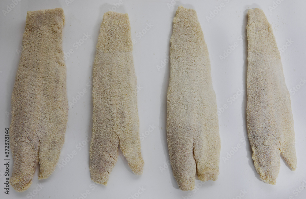 Cooking fish. Uncooked breaded hake fillets ready for frying. Stock ...