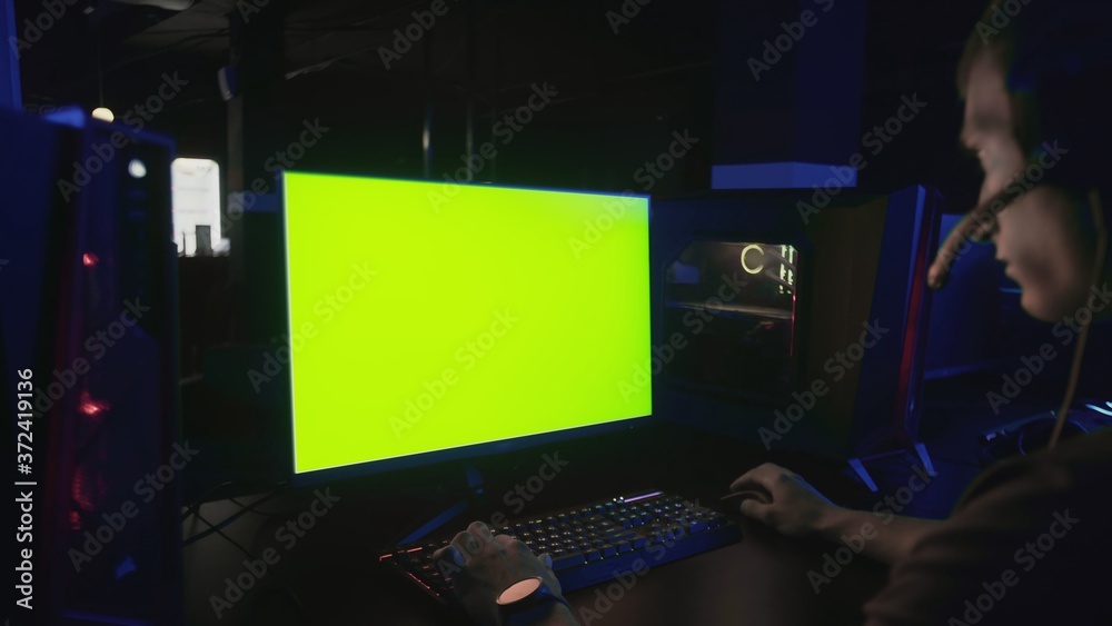 Back view of e cyber sport gamer play game with green screen monitor ...