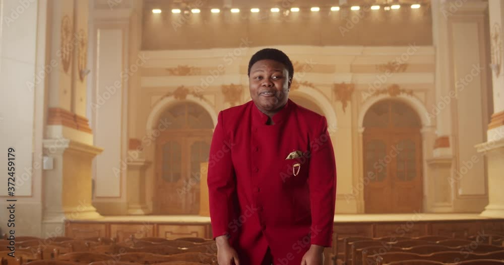 Young male musician in red clothes looking to camera and singing while ...