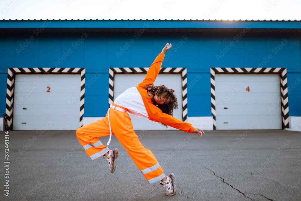 Young African American woman - dancer dancing in the street at sunset ...