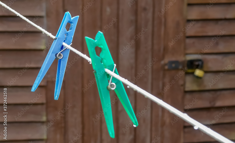Blue plastic clothes peg hangs upside down on a washing line after a ...