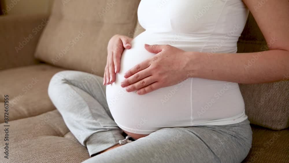 A Caring Mother Strokes A Naked Pregnant Tummy With Two Hands On Light