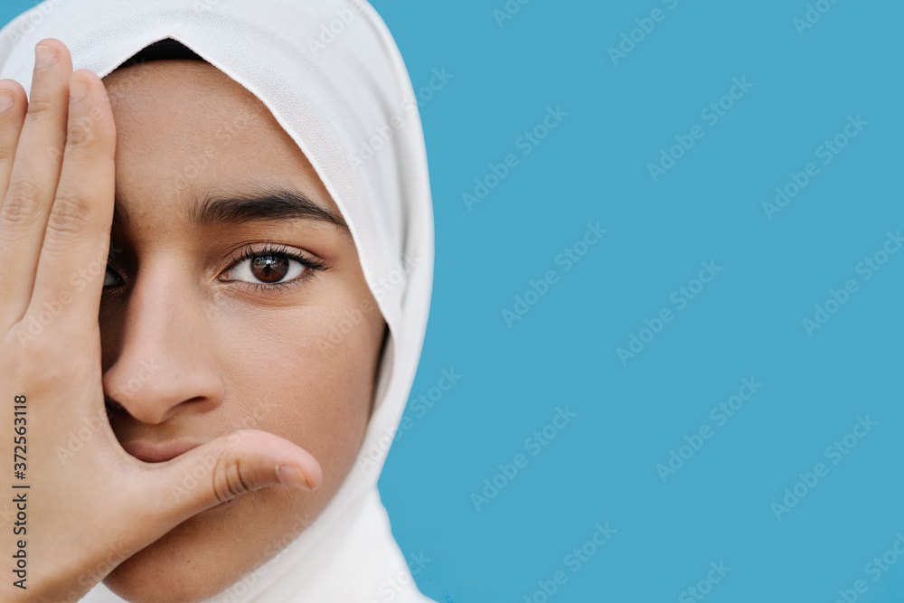 Muslim girl covering eye with hand against blue background Stock Photo ...