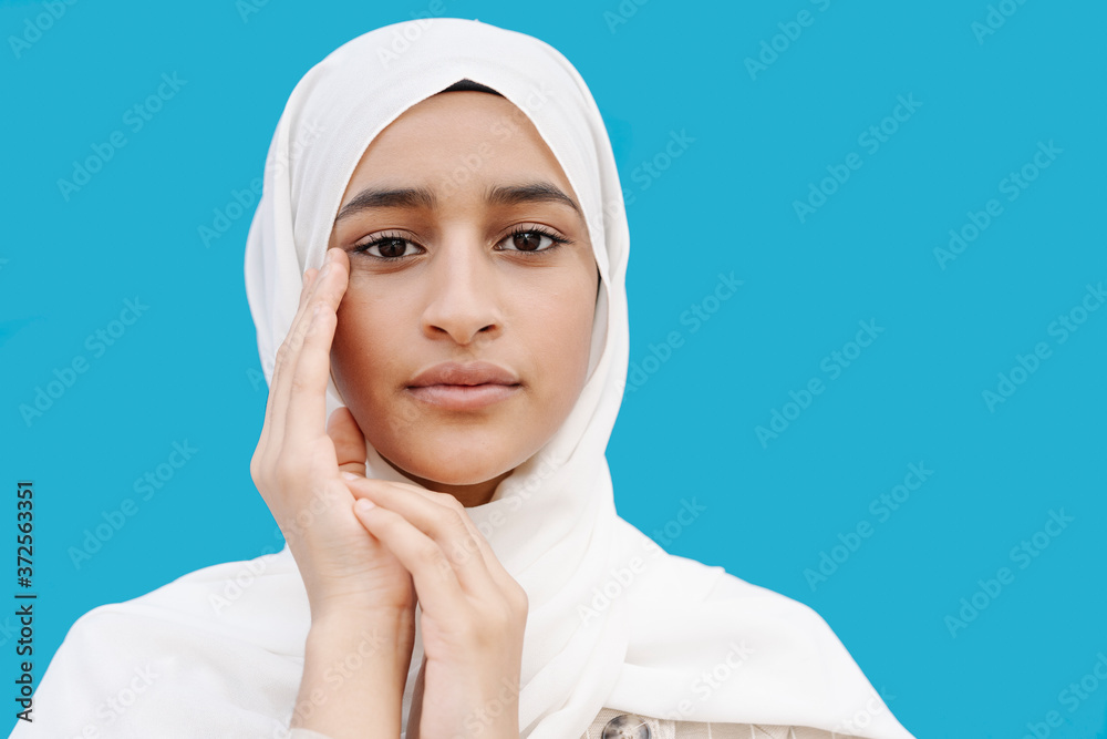 Muslim girl touching face against blue background Stock Photo | Adobe Stock
