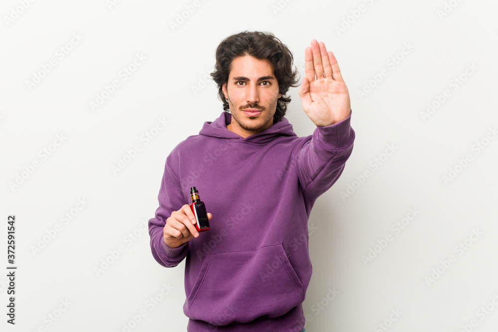 Young man holding a vaporizer standing with outstretched hand showing ...