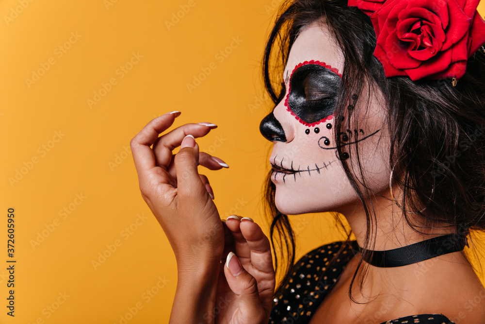 Tanned Mexican woman with traditional skull on her face poses in ...