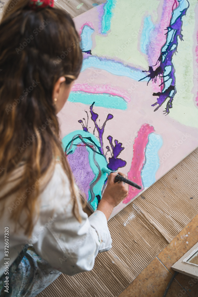 Cheerful barefoot female artist in dirty robe and gloves lying on ...