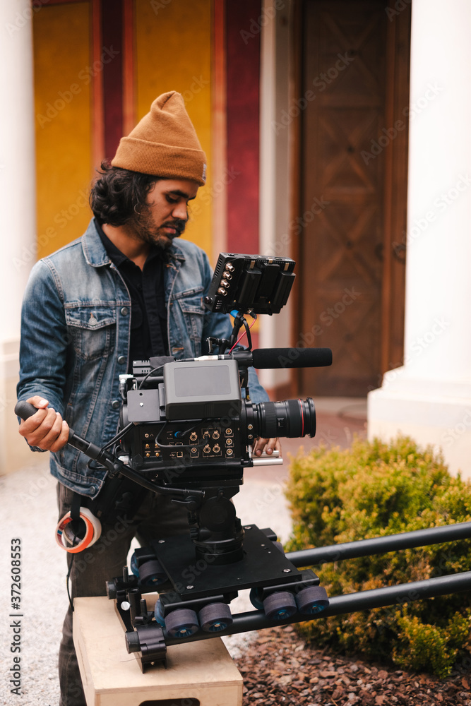 Side view faceless male video operator in casual denim jacket and hat ...