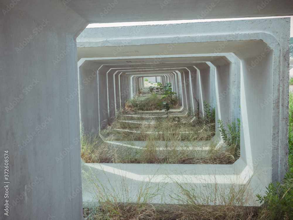 Perspective view of narrow passage with concrete walls and green grass ...