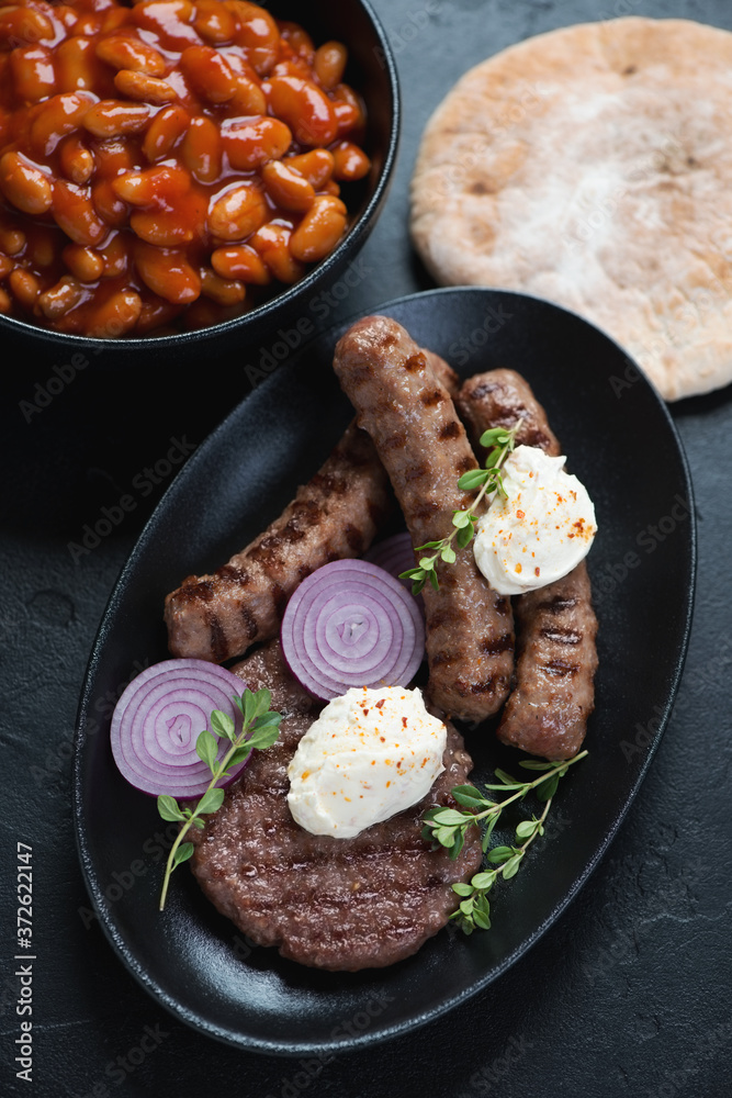 Grilled balkan meat patty or pljeskavica with cevapcici or skinless ...