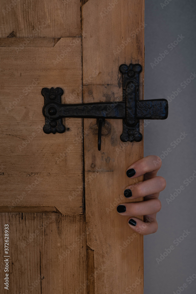 A creepy dark and moody shot of a hand holding onto a wooden antique ...