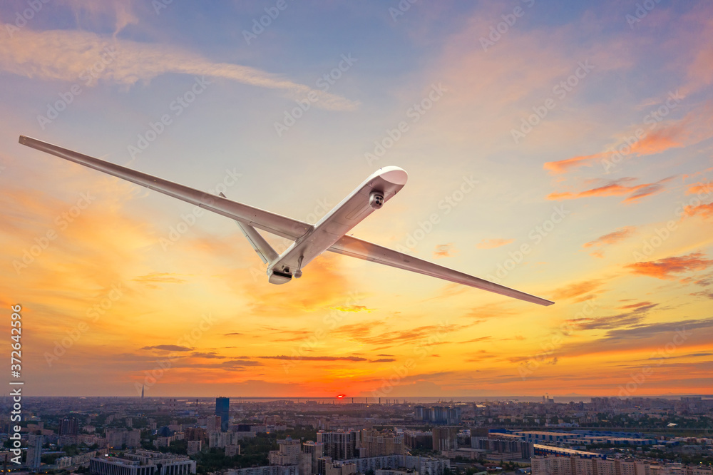 Unmanned military drone uav flying in the air over the city in evening ...