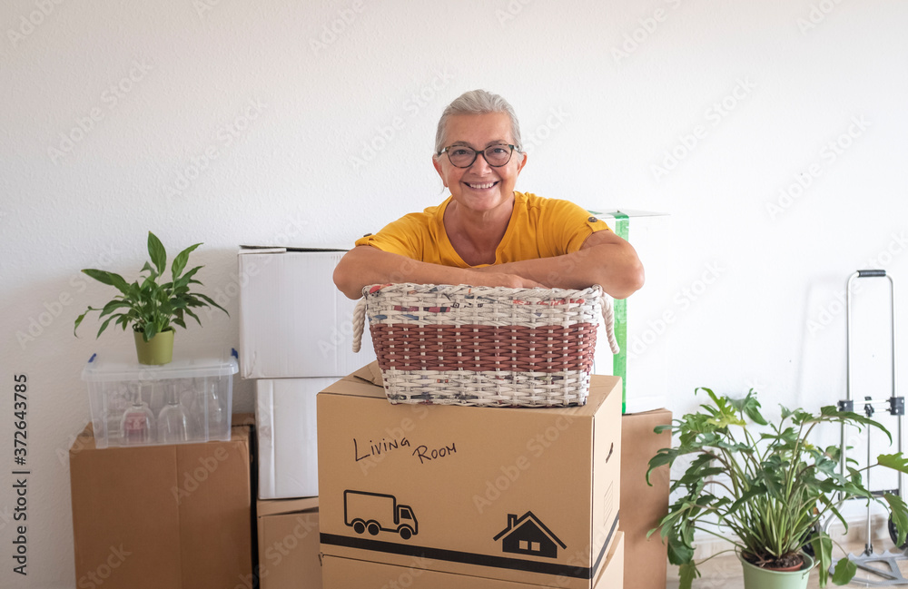 Portrait of smiling senior lady with gray hair resting in the new empty ...