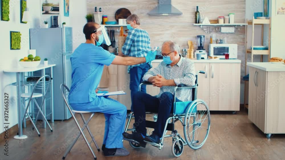 Doctor during home visit checking disabled patient in wheelchair ...