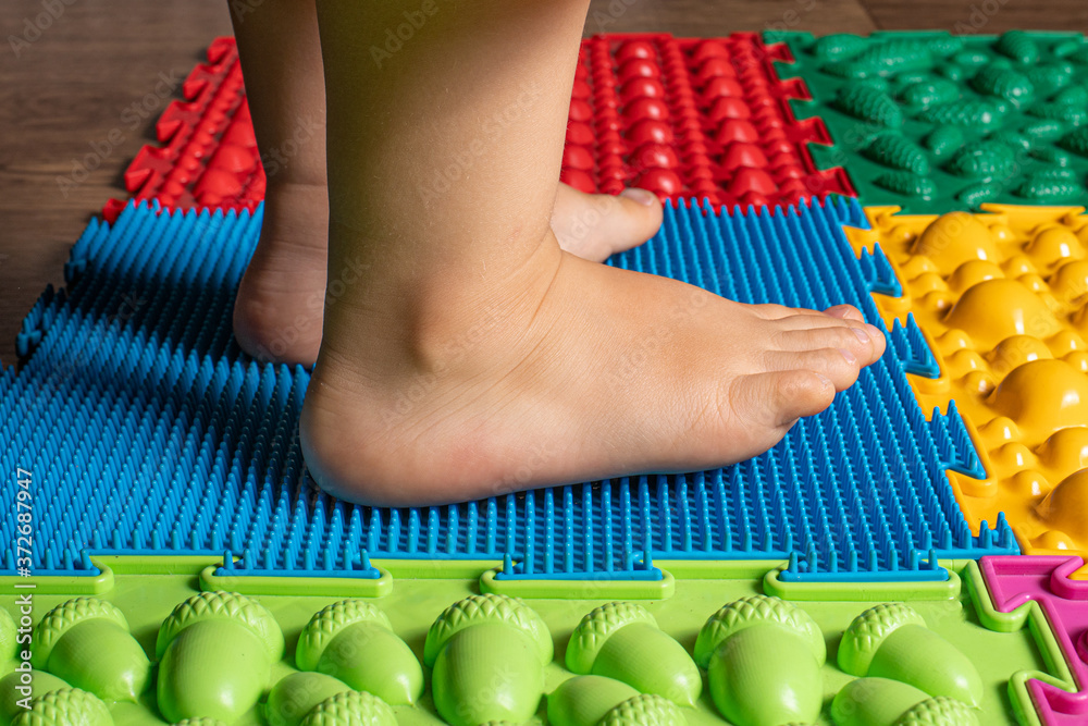 The legs of a small child on orthopedic mats. Bright surfaces for ...
