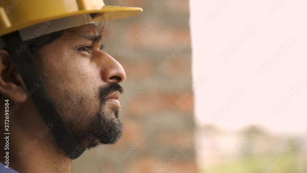 Head shot side view of construction worker in hardhat seeing outside ...