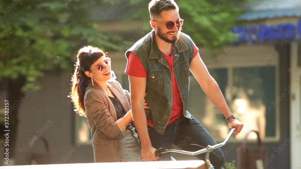 Young couple riding on bicycle together in the park. Romantic boyfriend cycling with happy ...