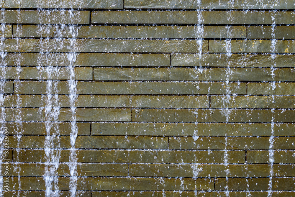 Water feature as a background, water running down a stone brick wall ...