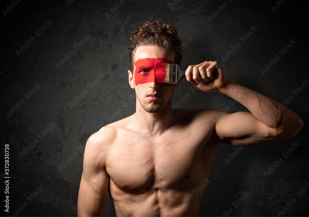Caucasian male with red paint on the face, covering his eye with a ...