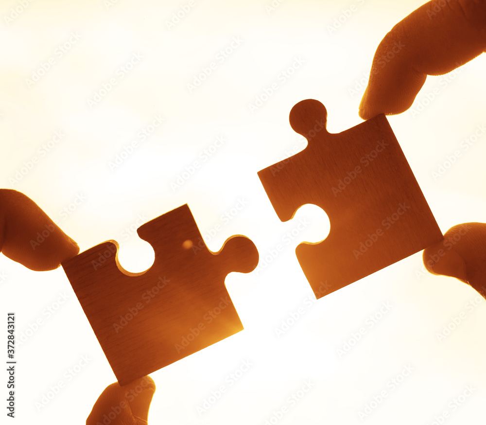 two hands trying to connect couple puzzle piece with sunset background ...