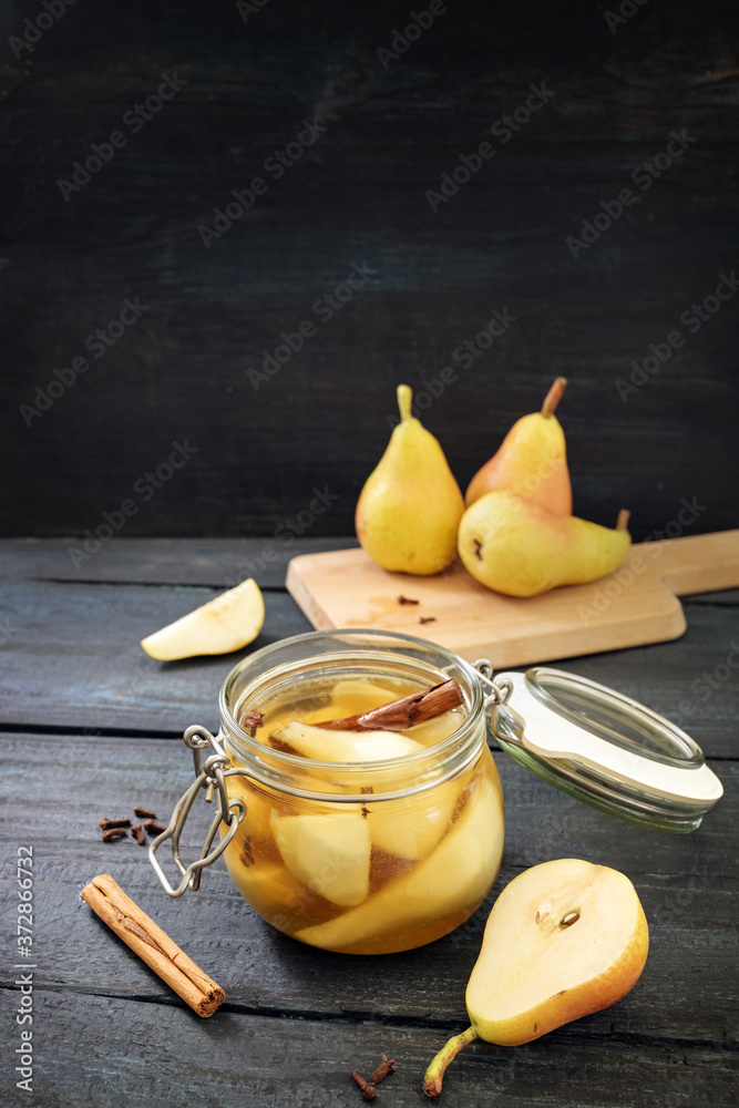 Canned pears with cinnamon and cloves in a glass jar and some fresh ...
