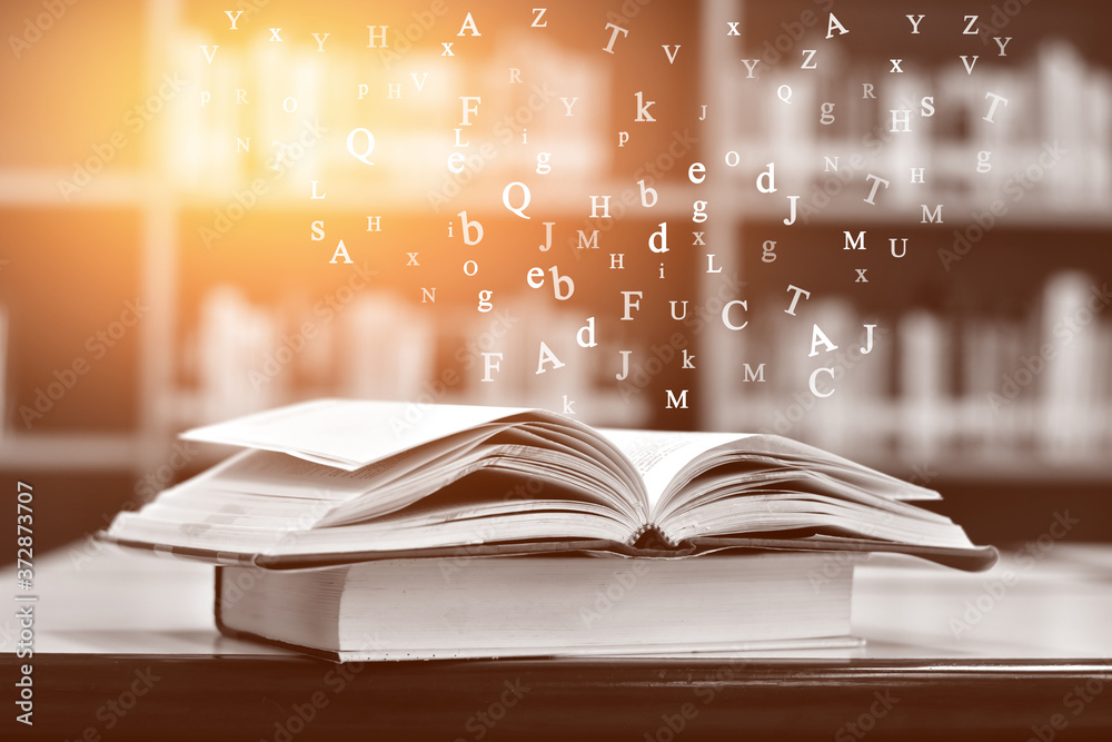 Open book on the table and English alphabet Floating above the book in ...