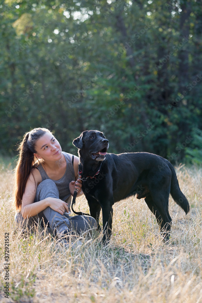 Young attractive sport girl with black Labrador in park. Healthy ...