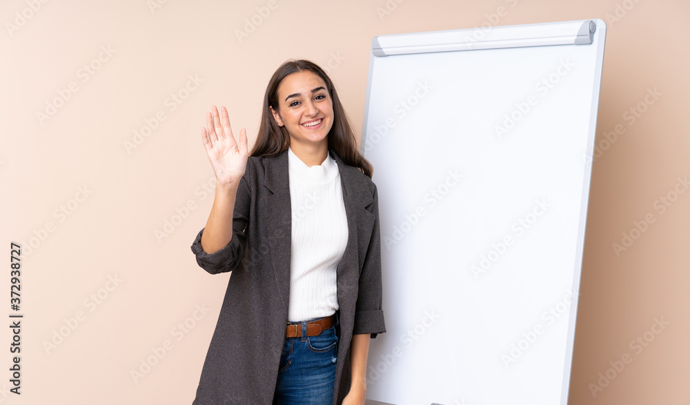 Young woman giving a presentation on white board saluting with hand ...