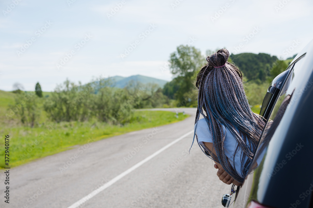 Beautiful girl with dreadlocks on her head pokes her head out of car ...