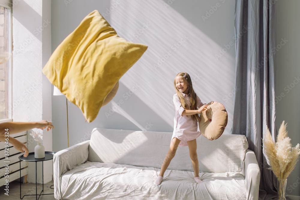 Foto de Little girl having fun and throwing pillows at home while ...