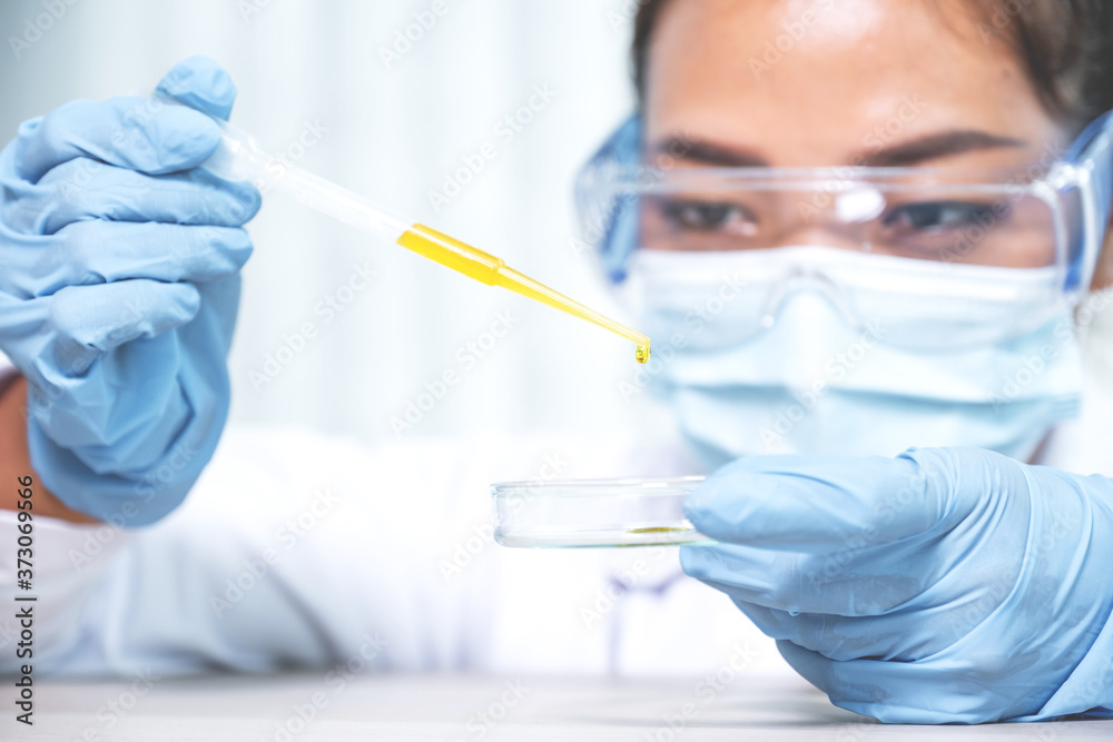 Doctor handhold the pipette and drop the yellow chemical liquid into a ...